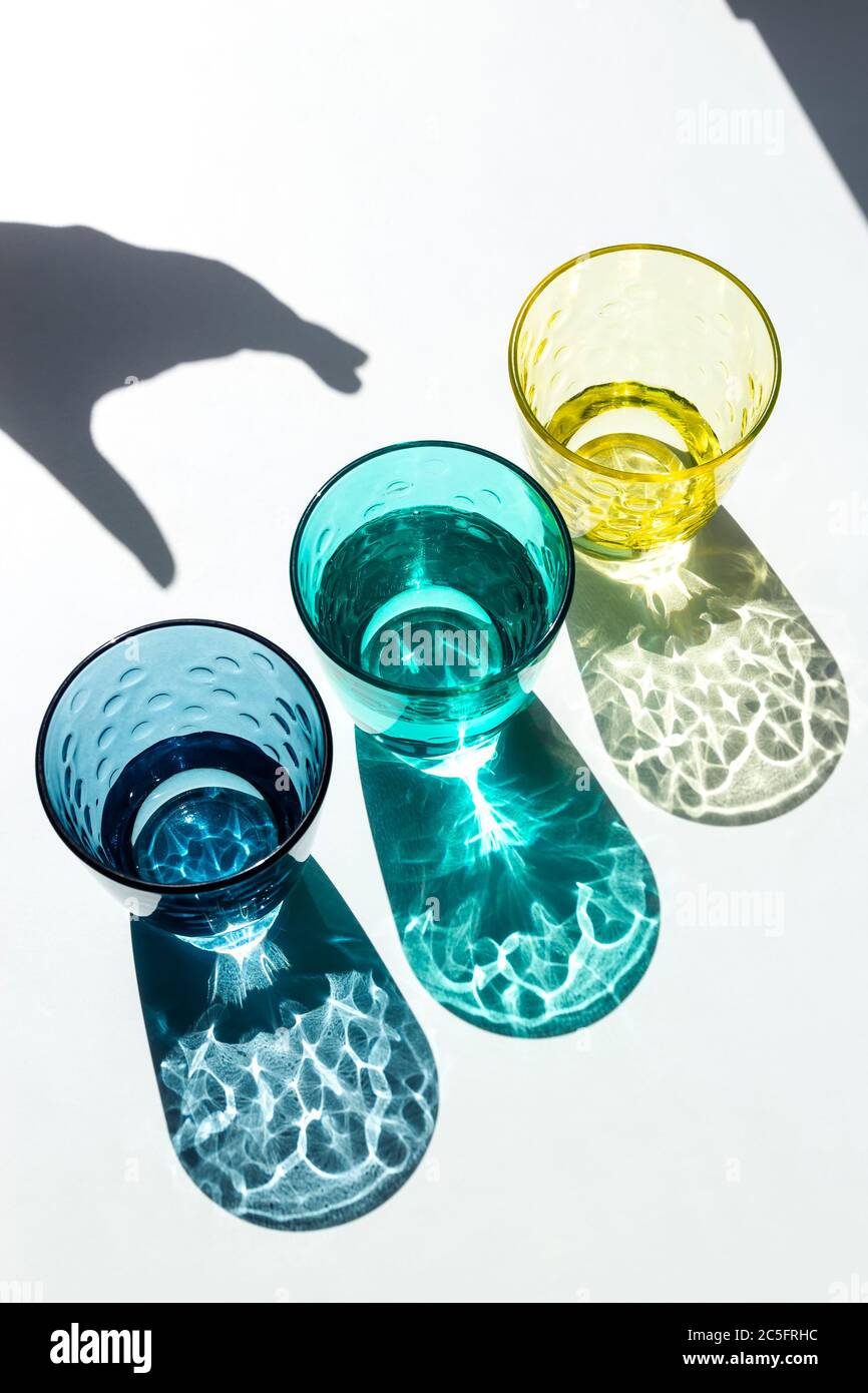 Shadow of a hand tries to take a glass cup full of water under the ...