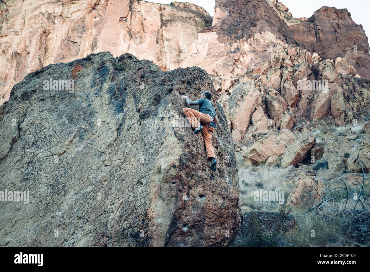 Male climber getting close to the top of the boulder in Smith Rock ...