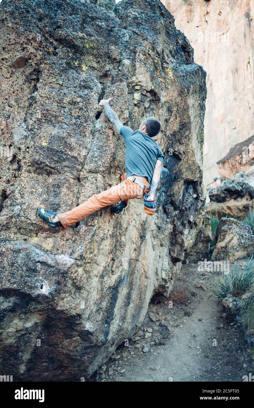 Male climber getting to the top of the boulder in Smith Rock park Stock ...