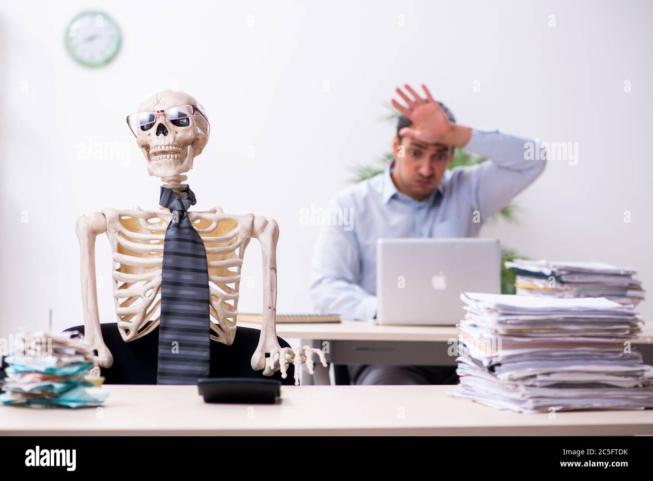 Young employee and skeleton in the office Stock Photo - Alamy
