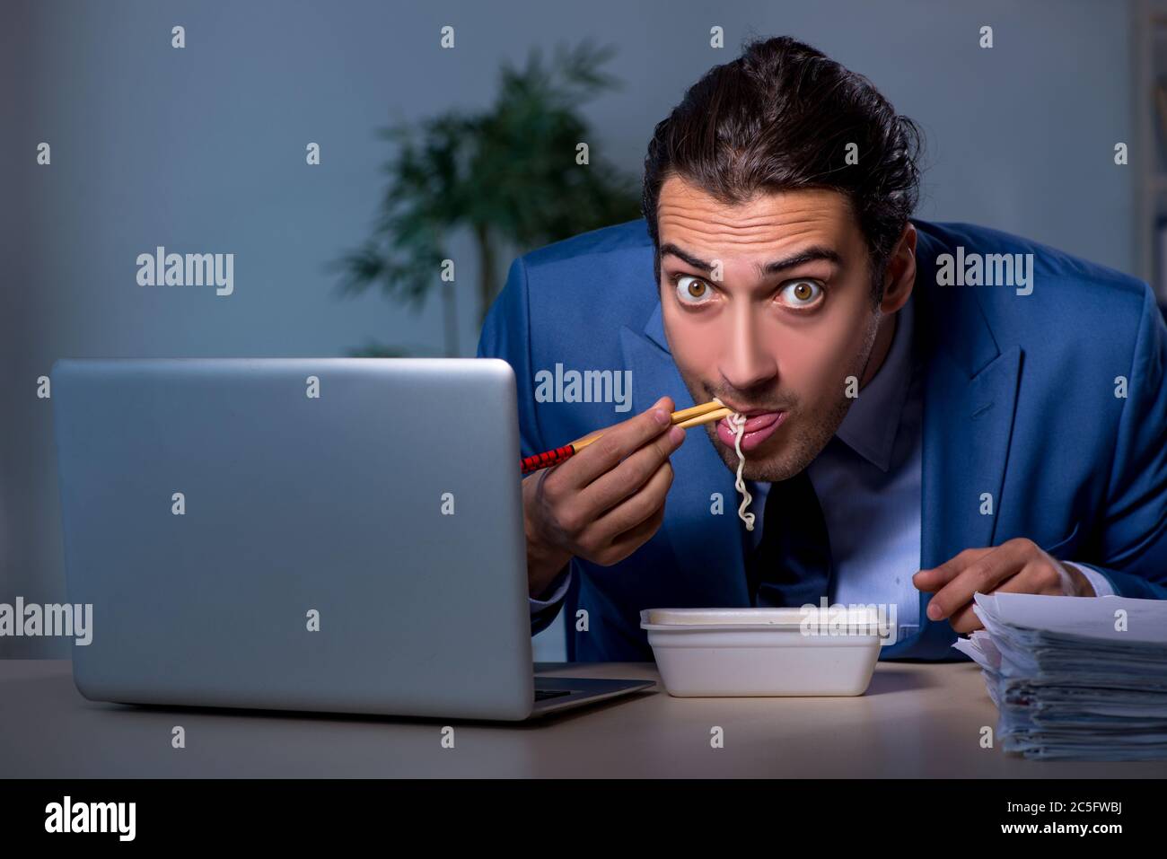 Hungry employee working late in office Stock Photo - Alamy