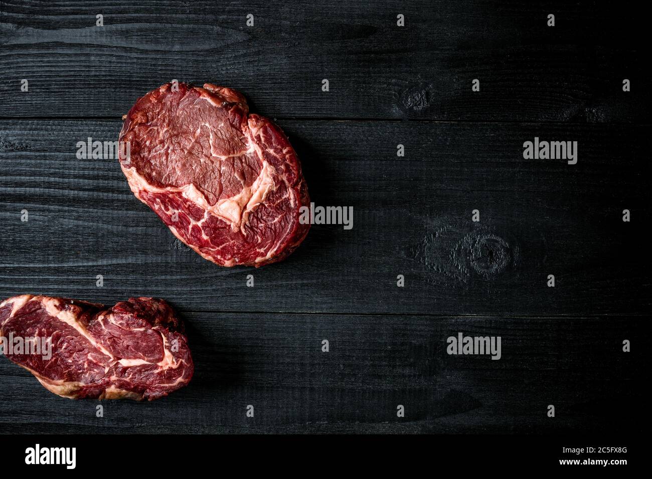 Fresh raw beef on black wooden background. Top view Stock Photo - Alamy