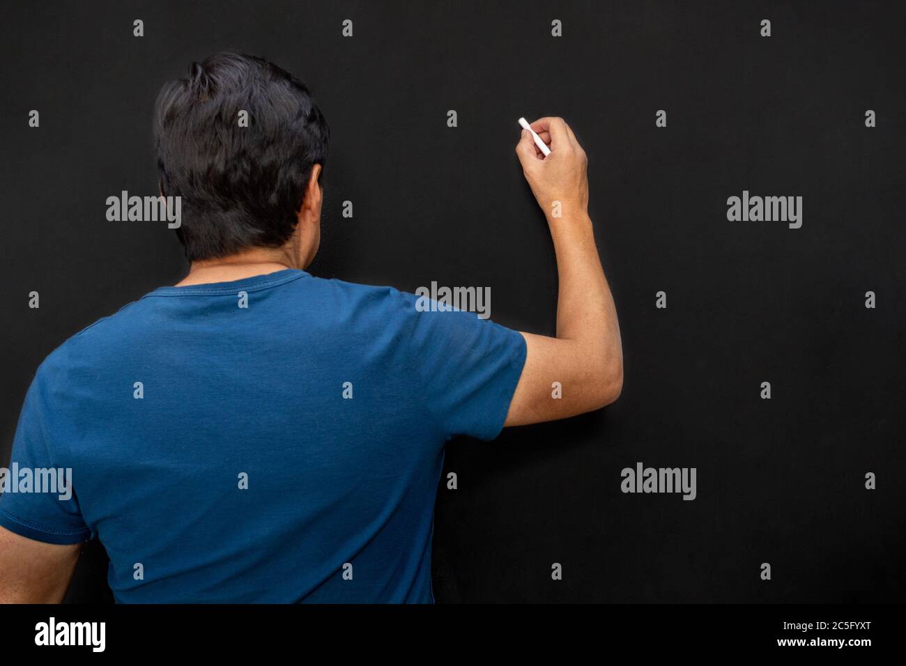 Class of a teacher with his back written on a blackboard with a chalk ...