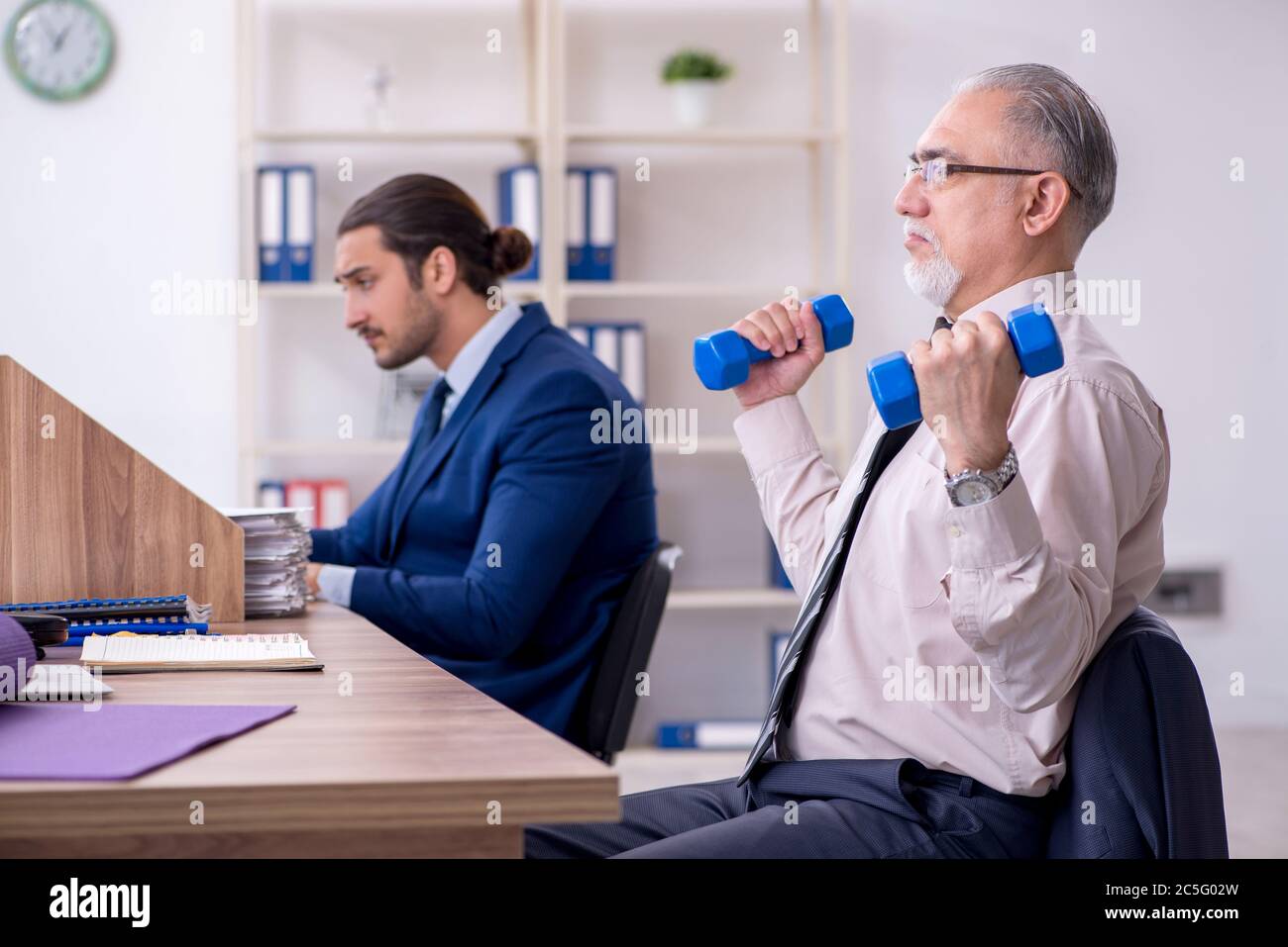 Two employees doing physical exercises at the workplace Stock Photo - Alamy