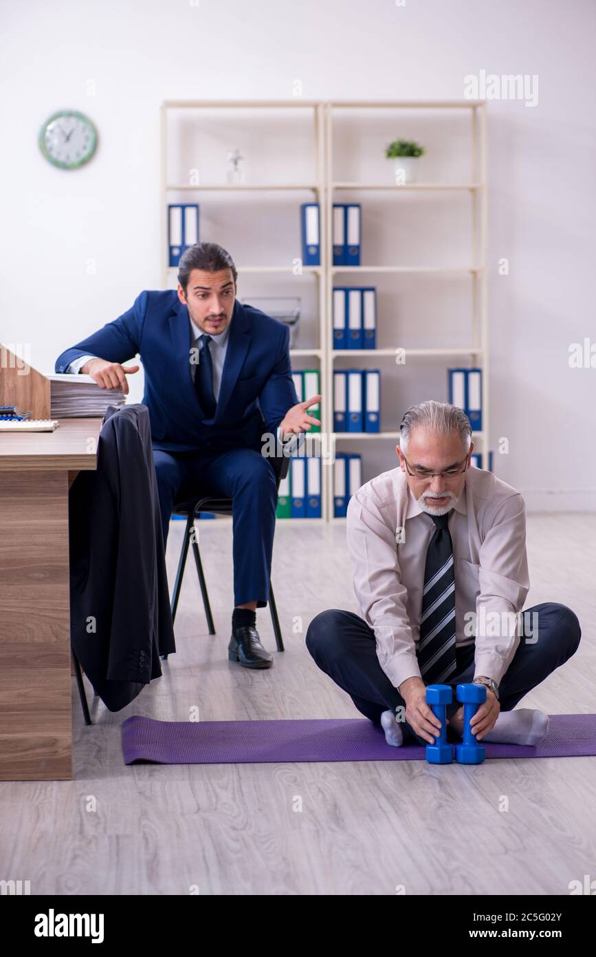 Two employees doing physical exercises at the workplace Stock Photo - Alamy