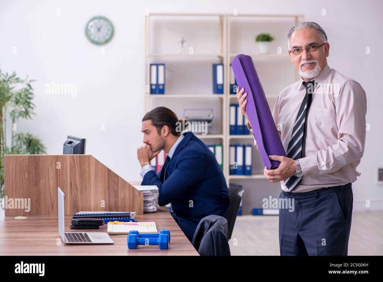 Two employees doing physical exercises at the workplace Stock Photo - Alamy