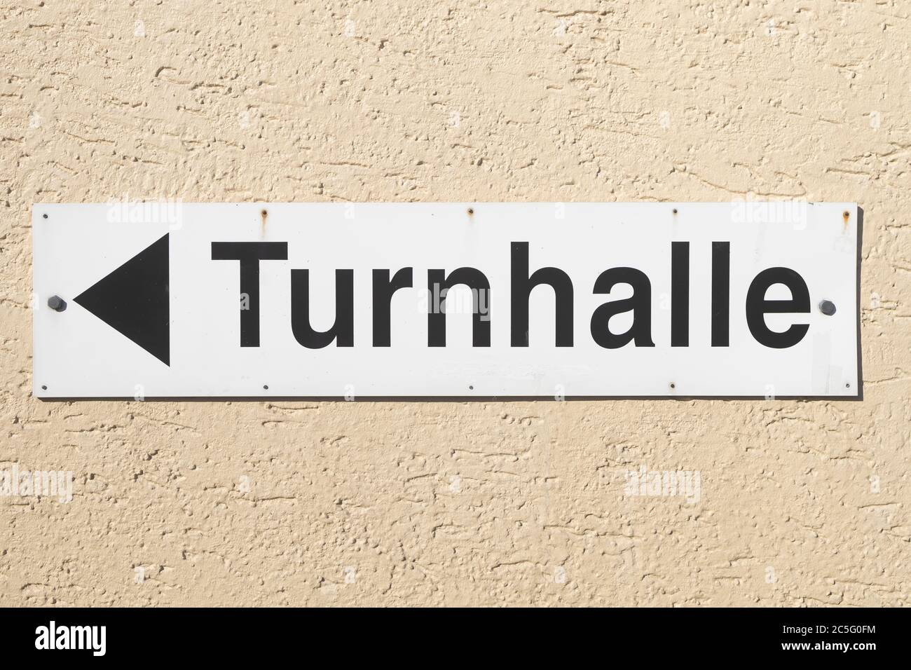 Gym Sign in german language hanging on house fassade with black arrow ...