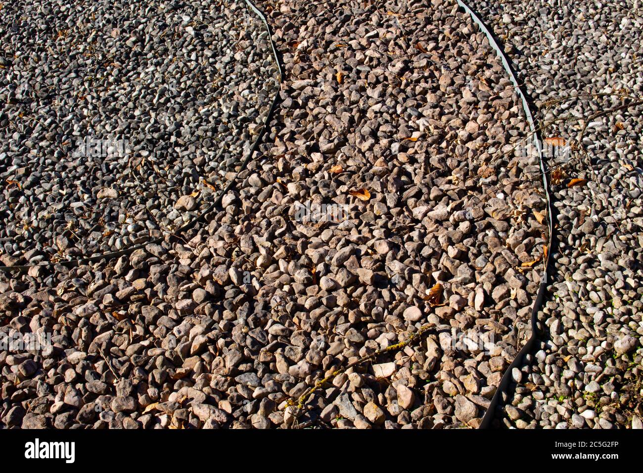 Metal edging separating dirt and different colors of gravel in a park ...