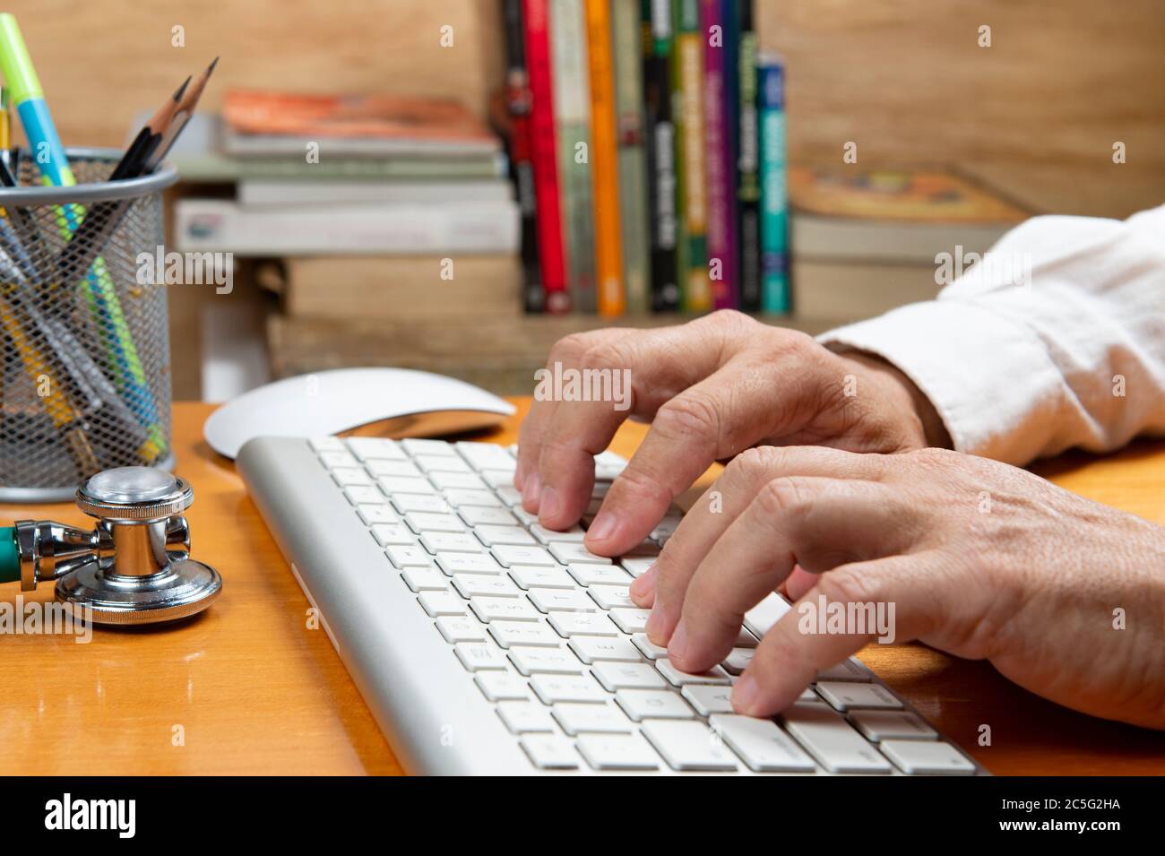 Person with hand on keyboard at an office desk with a stethoscope ...