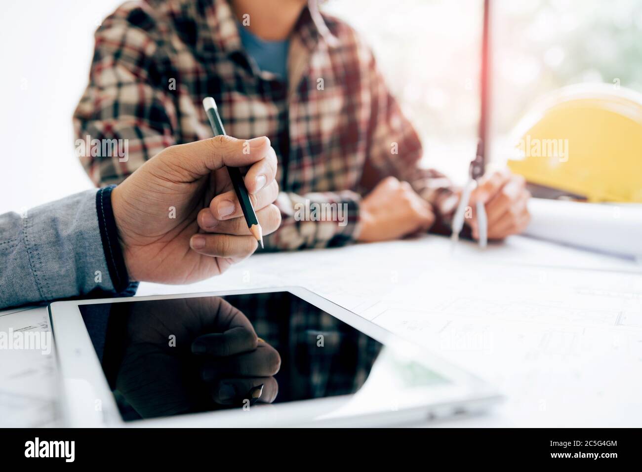 Male engineering using digital tablet with architectural plan on desk ...