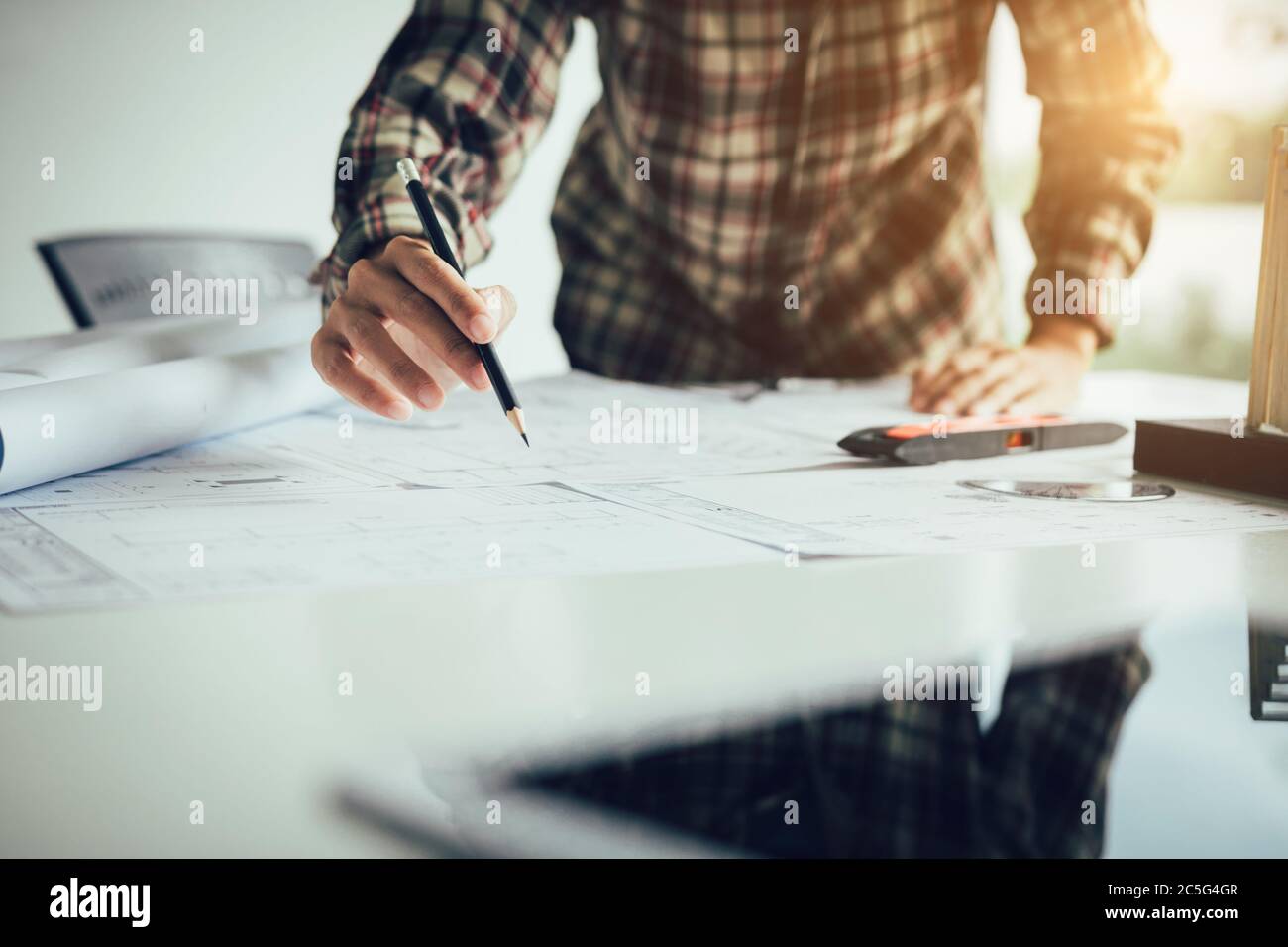 Hand of young engineering man drawing on blueprint at table in office ...