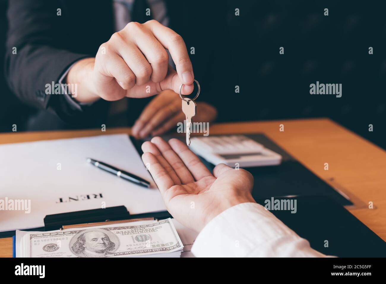 Close up of hand real estate agent passes the key to new homeowners in ...