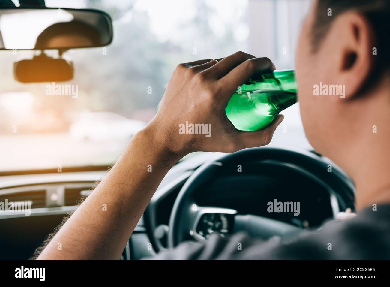 Asian guy with drunk alcohol, drinking beer while driving on the road ...