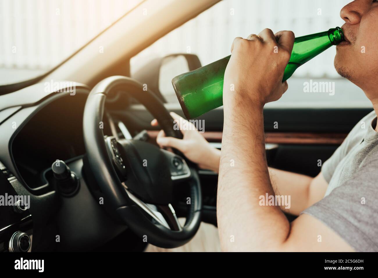 Asian guy with drunk alcohol, drinking beer while driving on the road ...