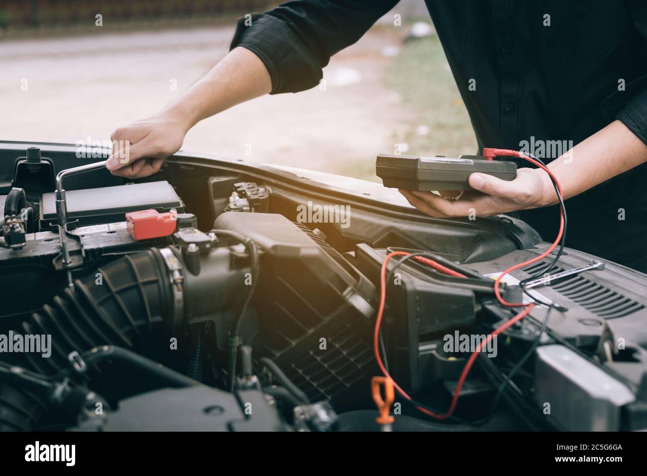 Car mechanic is checking the engine and holding the battery gauge Stock ...