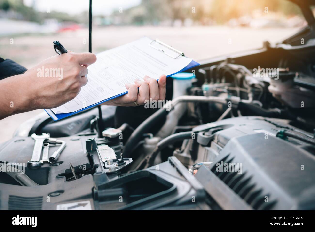 Asian car mechanic doing a check list and note report on paper ...