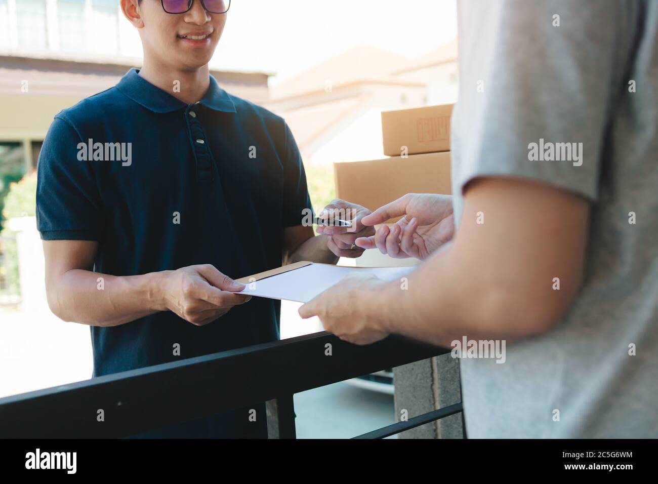 Young asian man smiling while delivering a cardboard box to the woman ...