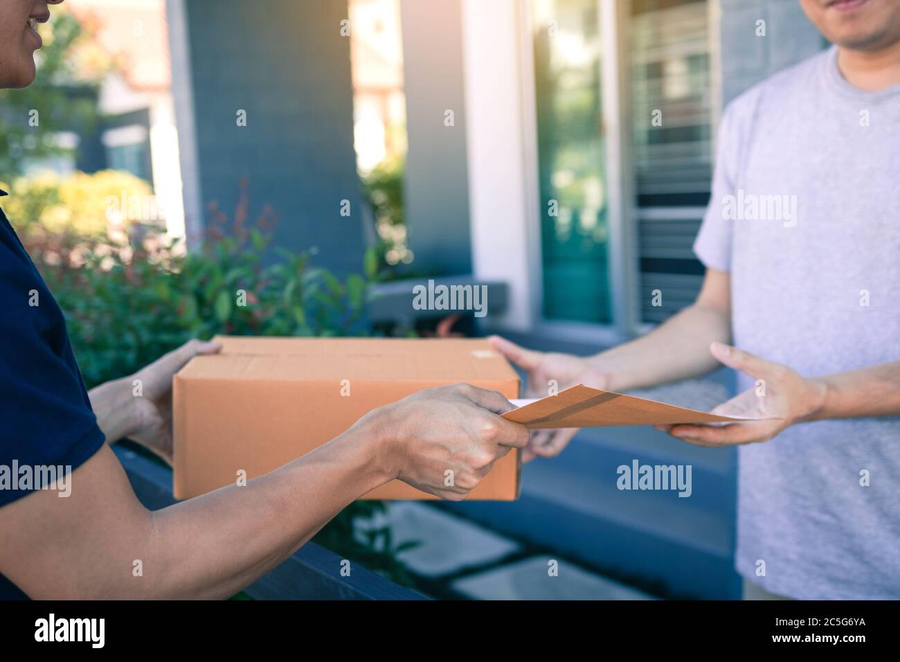 Young asian man smiling while delivering a cardboard box to the woman ...