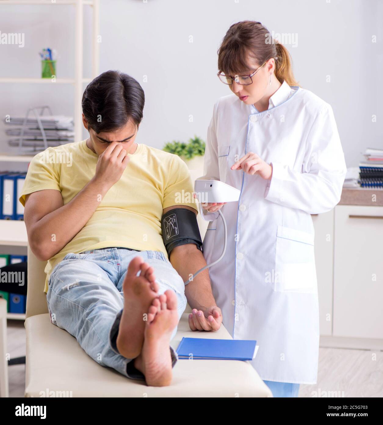 The young doctor checking patients blood pressure Stock Photo - Alamy