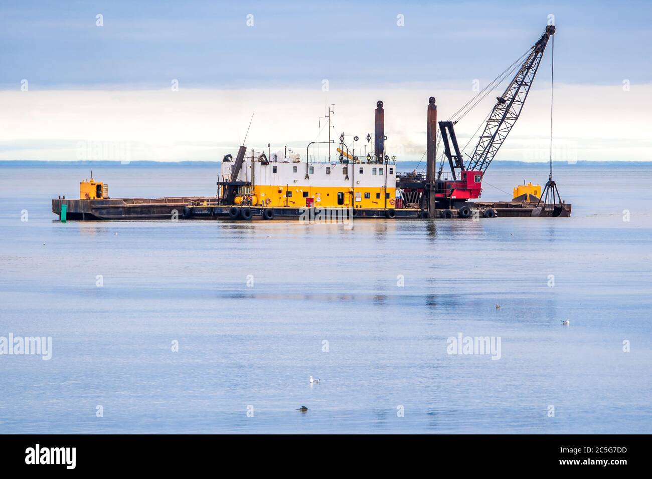An old dredging barge in the ocean. Barge is yellow and white with a ...