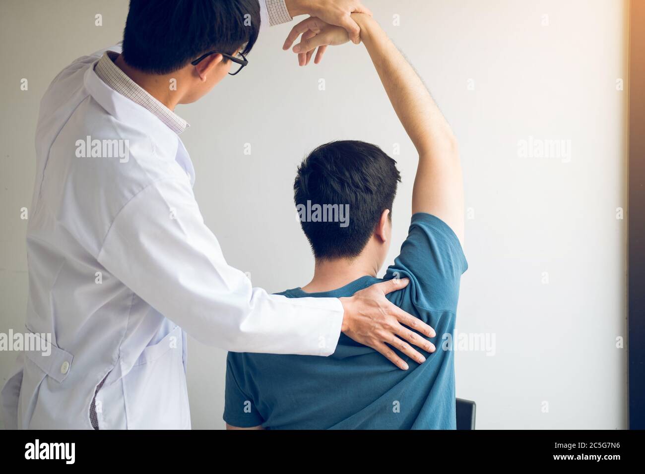 Chiropractor stretching a young man arm in medical office Stock Photo ...