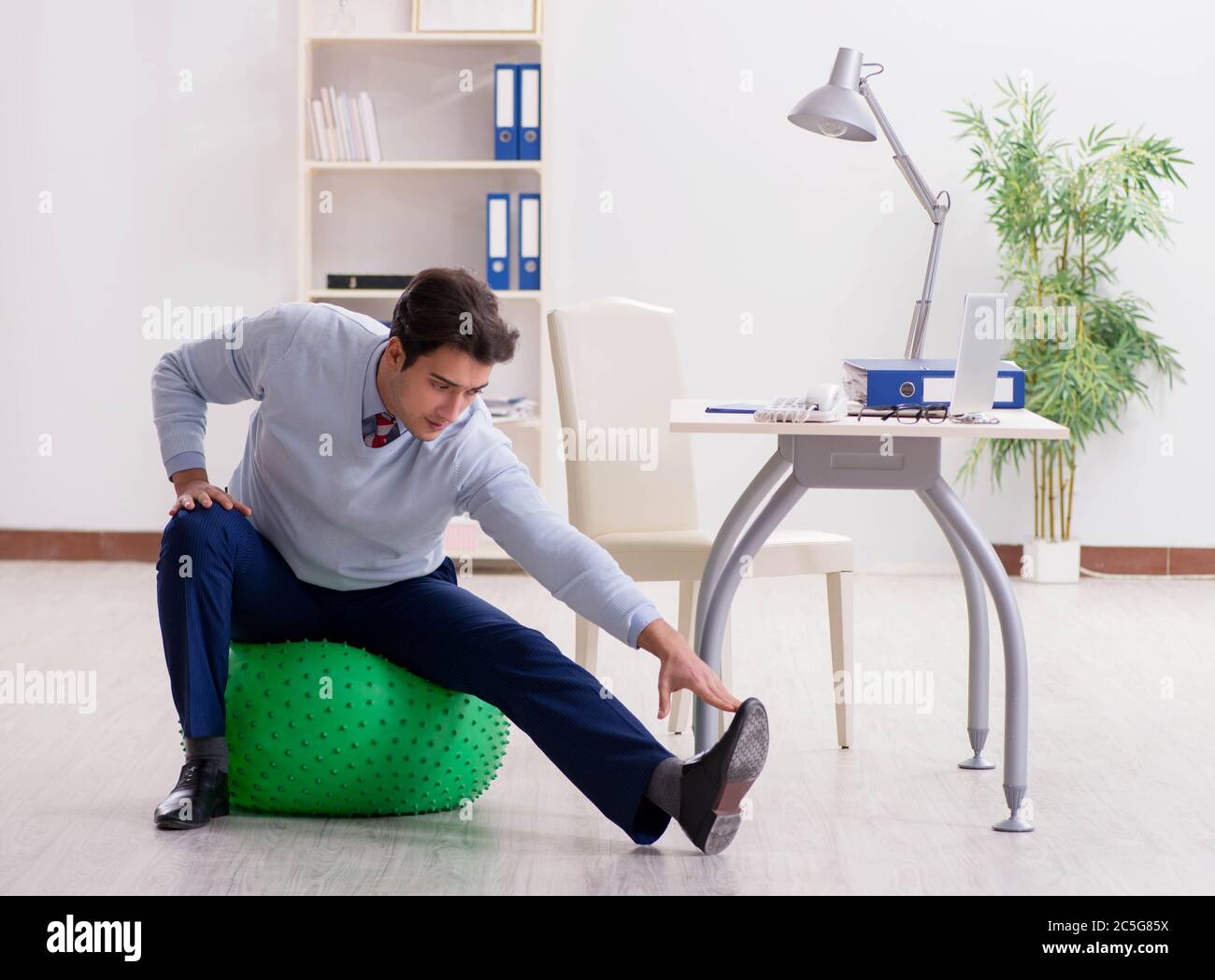 The employee exercising with swiss ball during lunch break Stock Photo ...