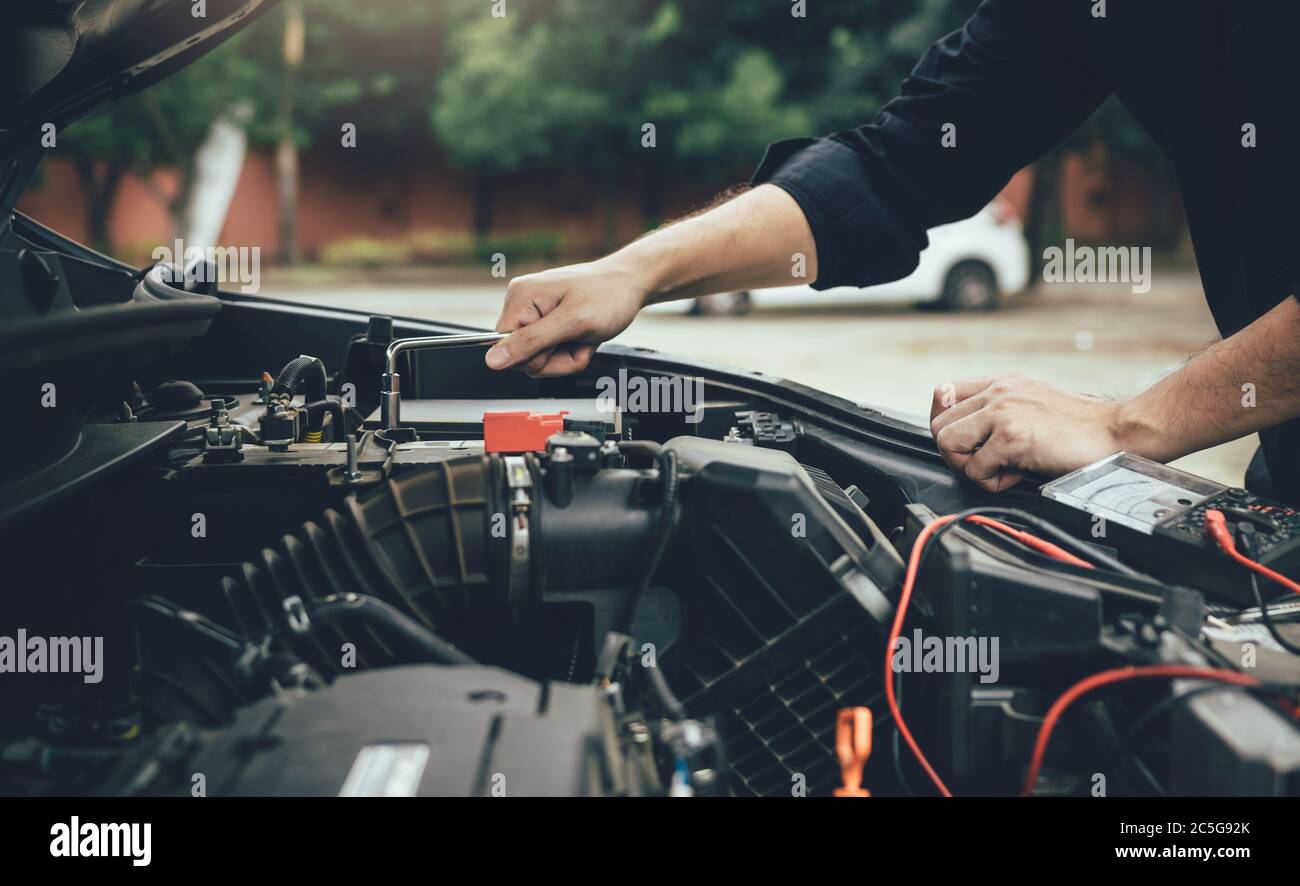 Car mechanic is checking the engine and holding the battery gauge Stock ...