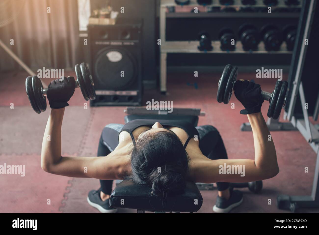 Beautiful asian woman lifting weights dumbbell for her chest near ...