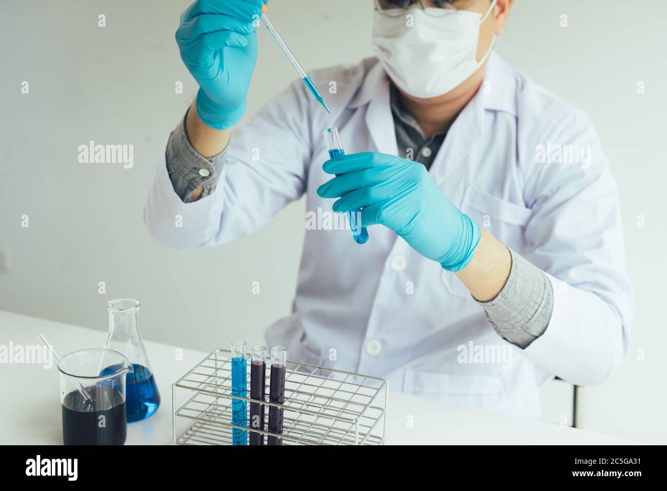Chemist scientist conducts experiments by synthesising compounds with ...