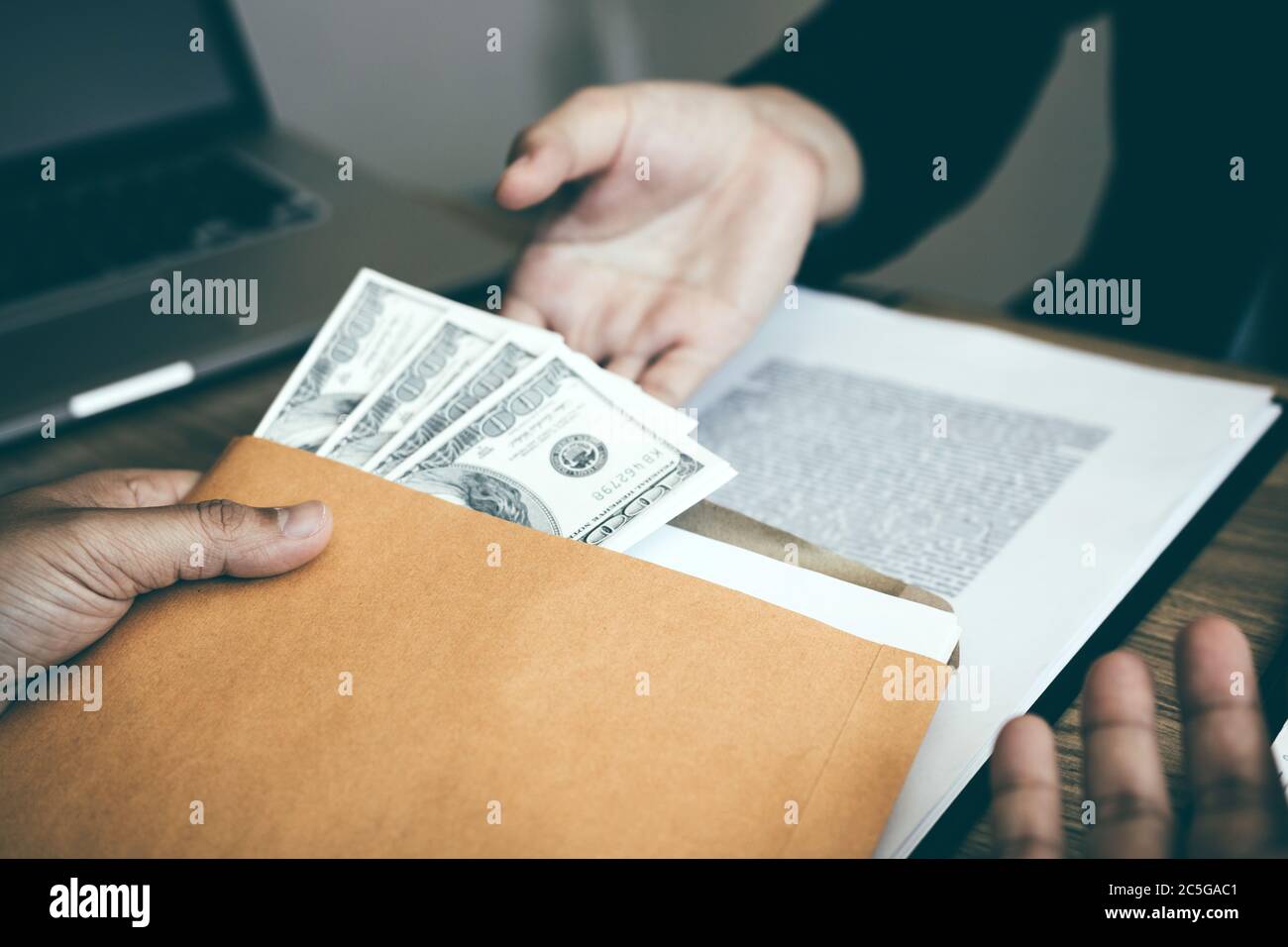 Businessman secretly giving a bribe by giving money bills in envelope ...