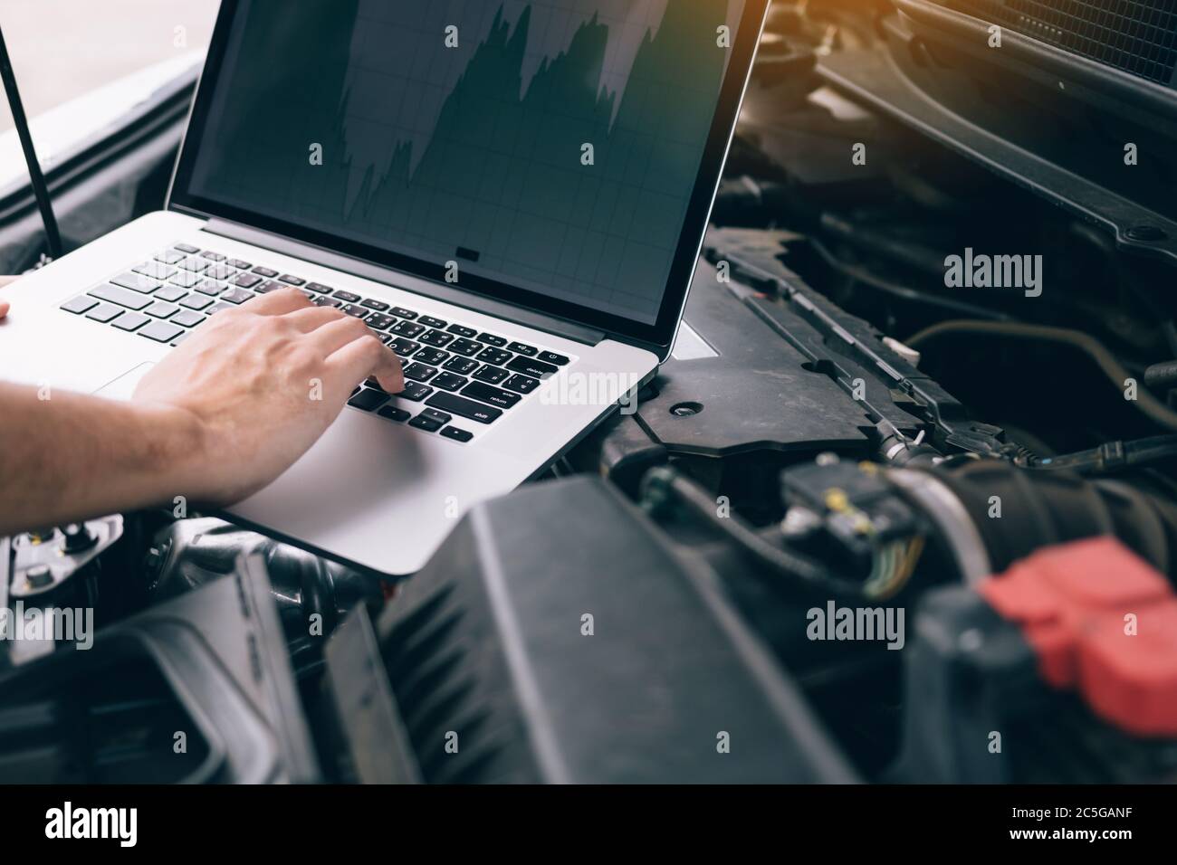 Car repair technicians use laptop computers to measure engine values ...