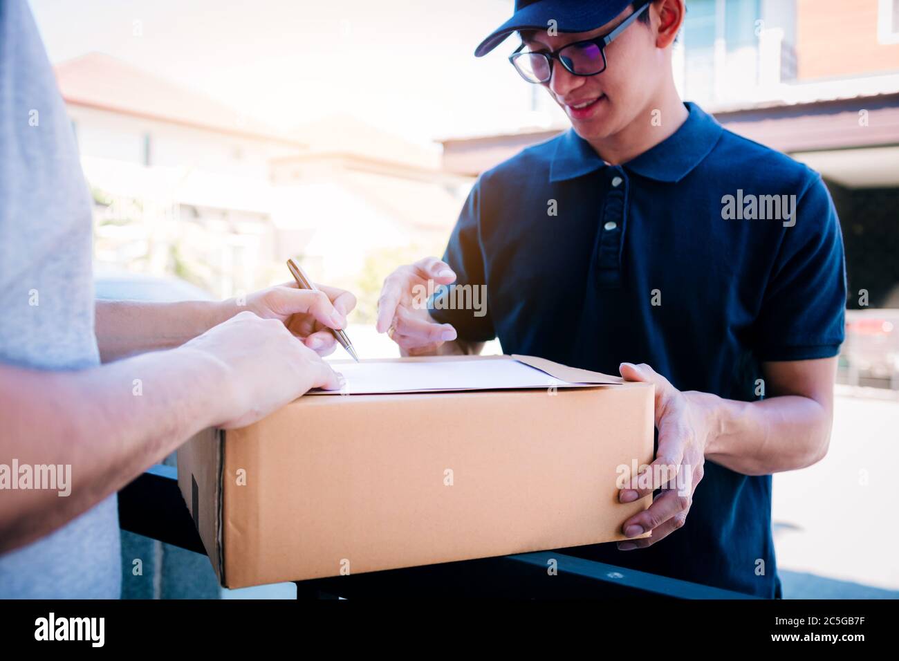 Delivery young man standing at the door of home and carrying parcels ...