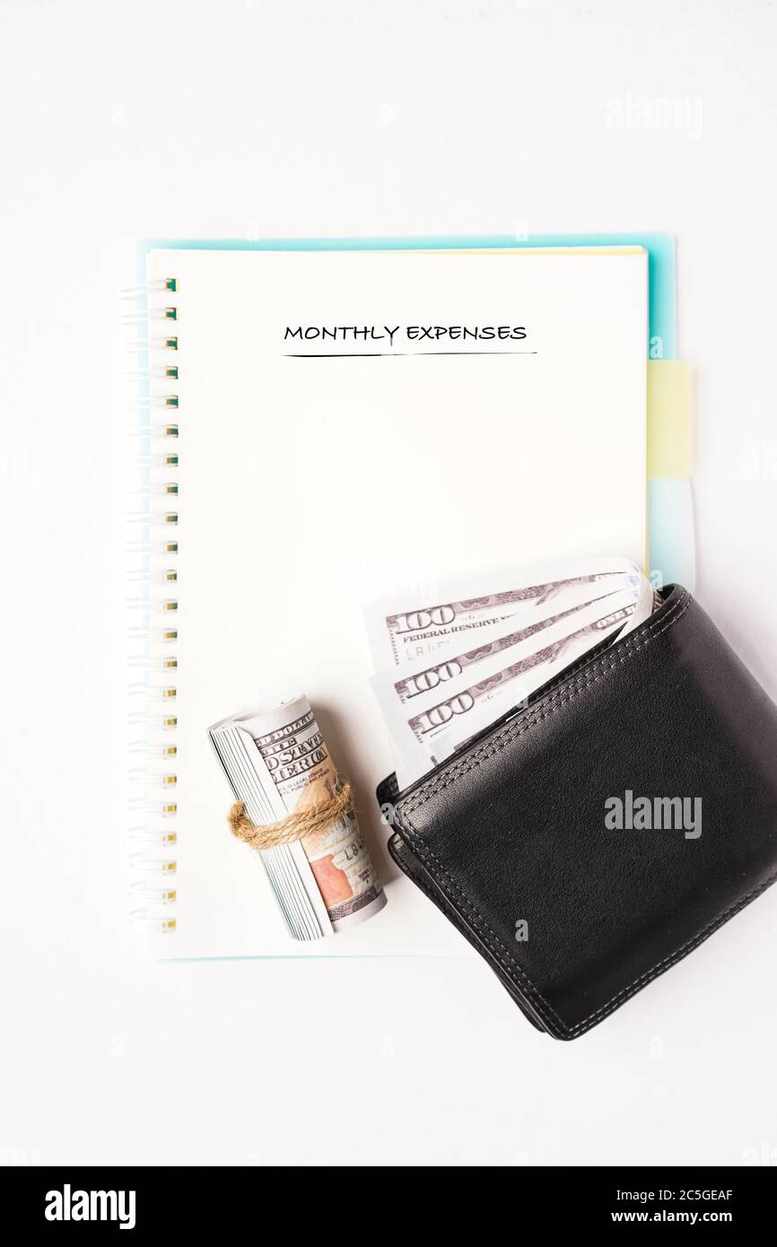 “Monthly Expenses” wordings on a notebook with wallets on the side ...