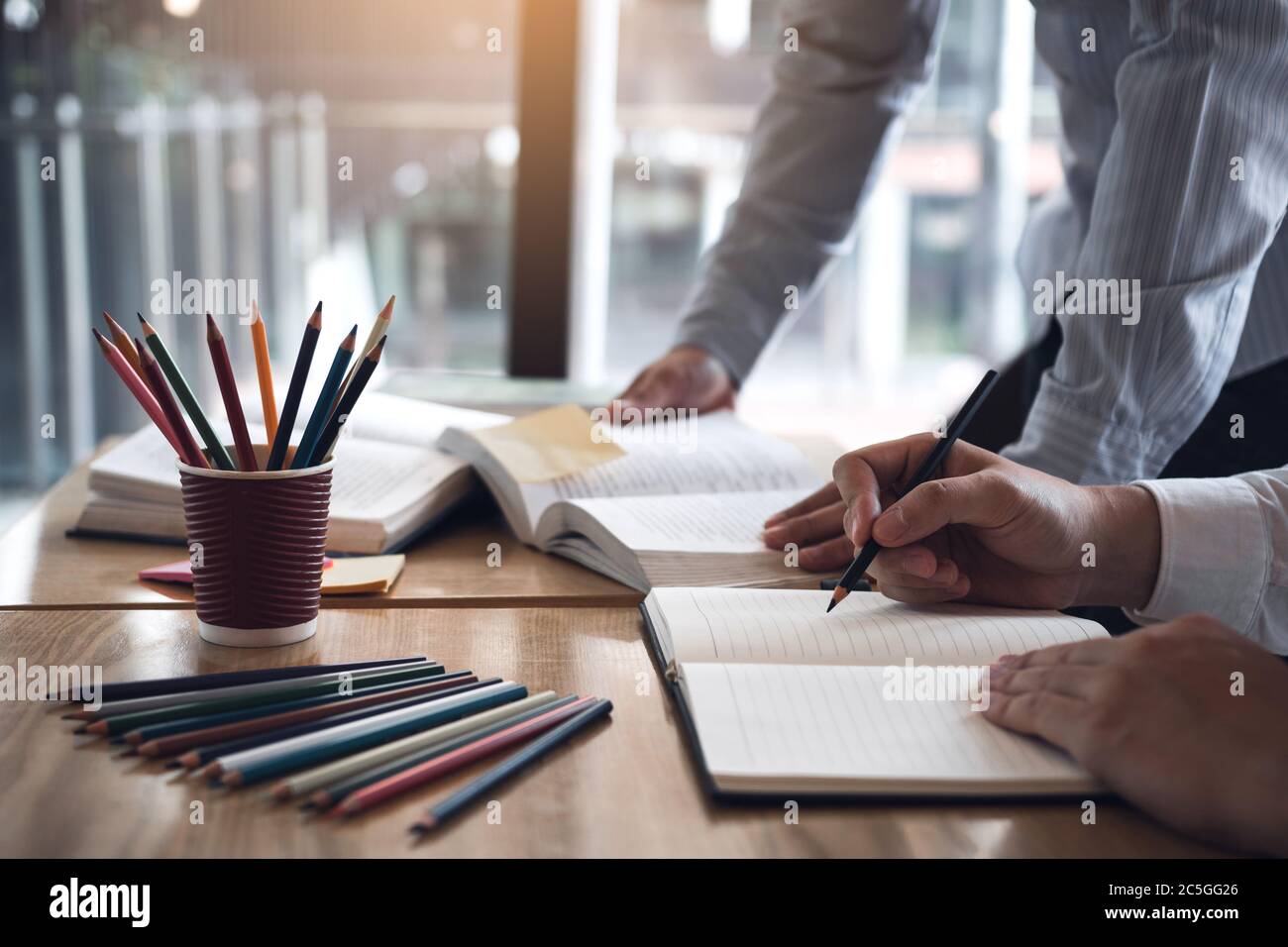 Two student reading textbook for test together in library Stock Photo ...