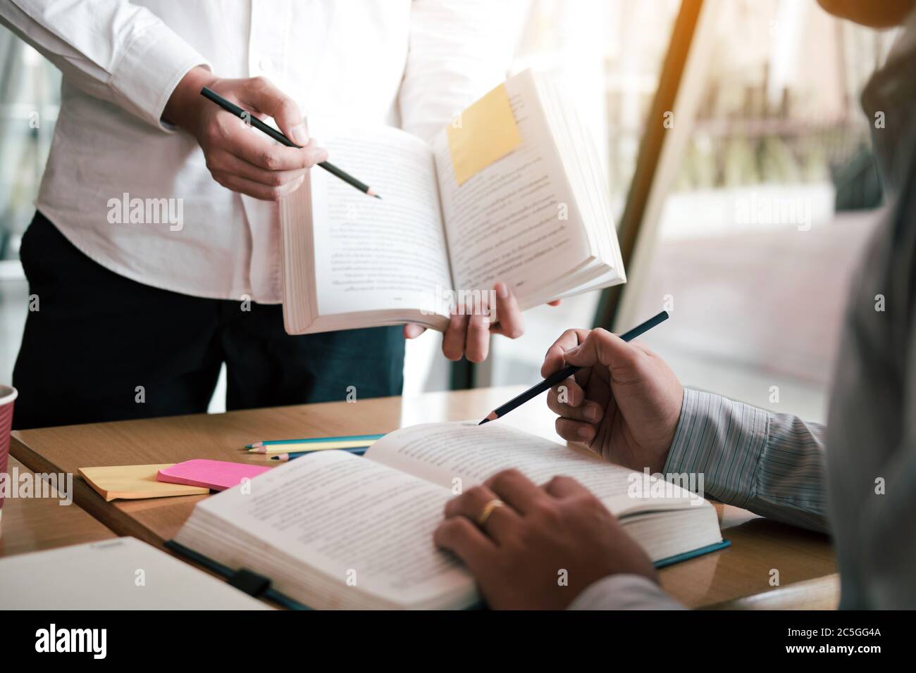 Two student reading textbook for test together in library Stock Photo ...