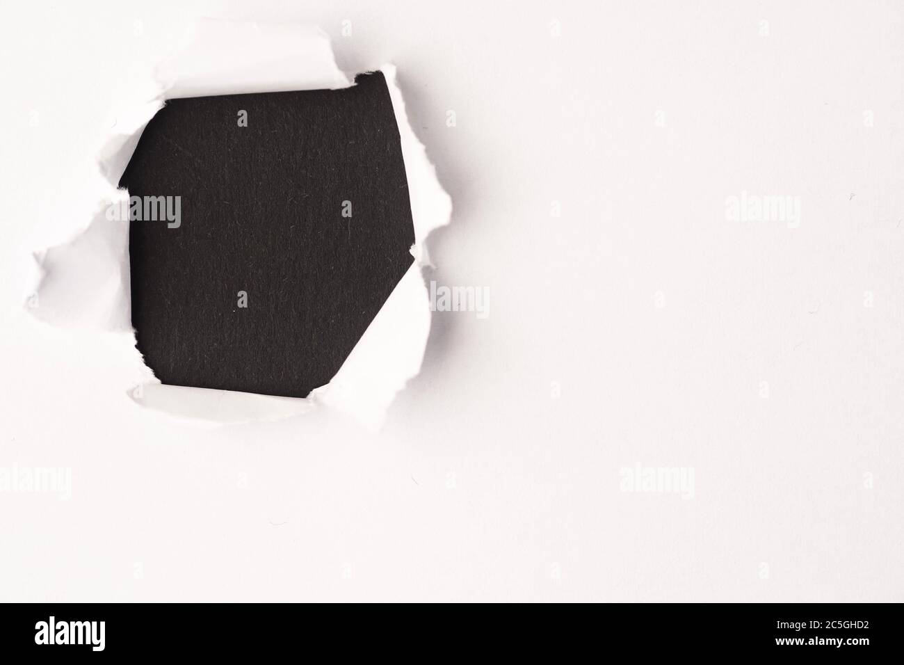 Hole in the paper with torn sides Stock Photo - Alamy