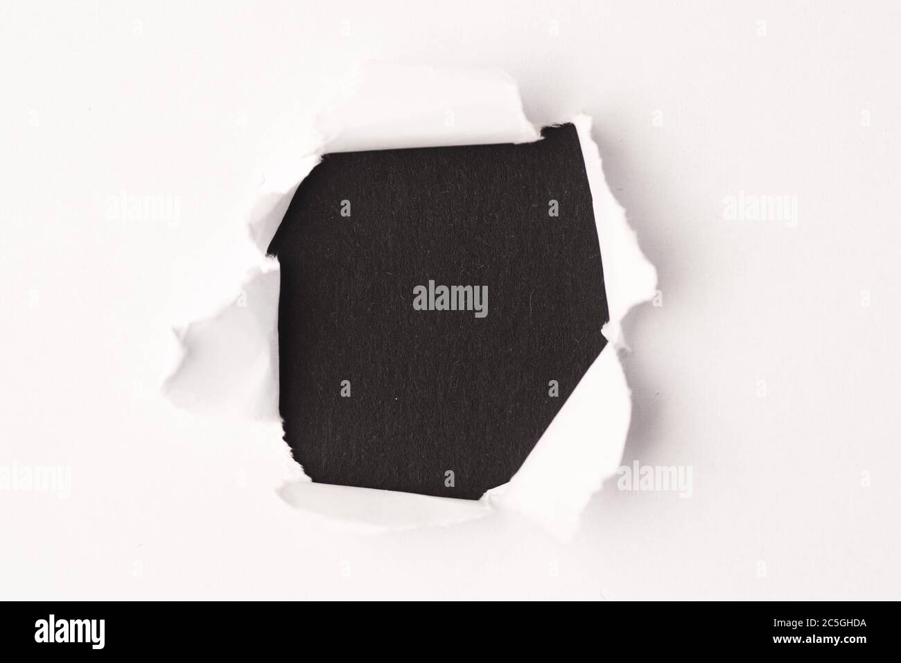 Hole in the paper with torn sides Stock Photo - Alamy