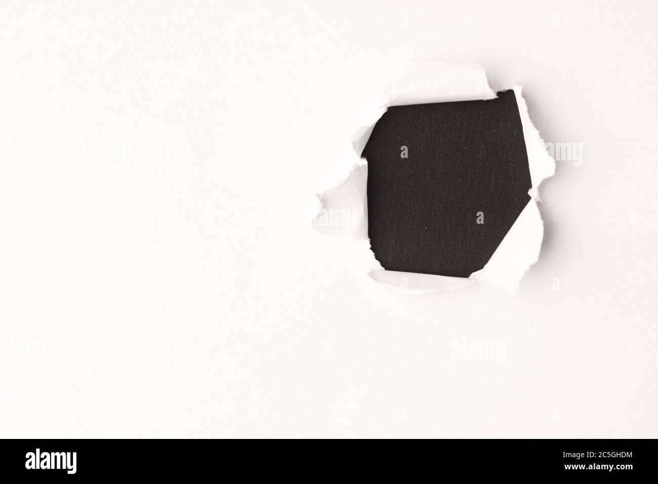 Hole in the paper with torn sides Stock Photo - Alamy