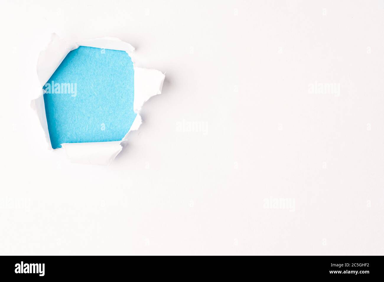 Hole in the paper with torn sides Stock Photo - Alamy