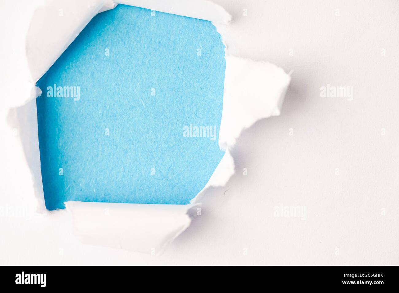 Hole in the paper with torn sides Stock Photo - Alamy