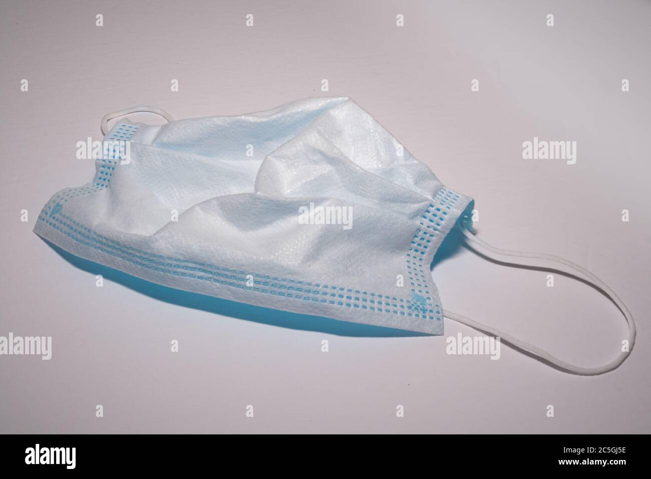 A single, white, hospital-grade medical face mask is laid out on a ...