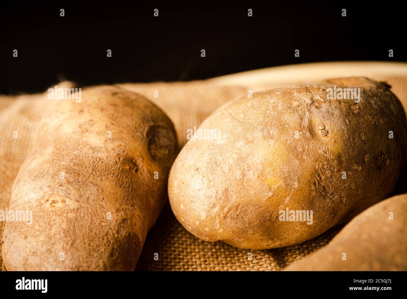 Fresh Potatoes on a rag with dark background Stock Photo - Alamy