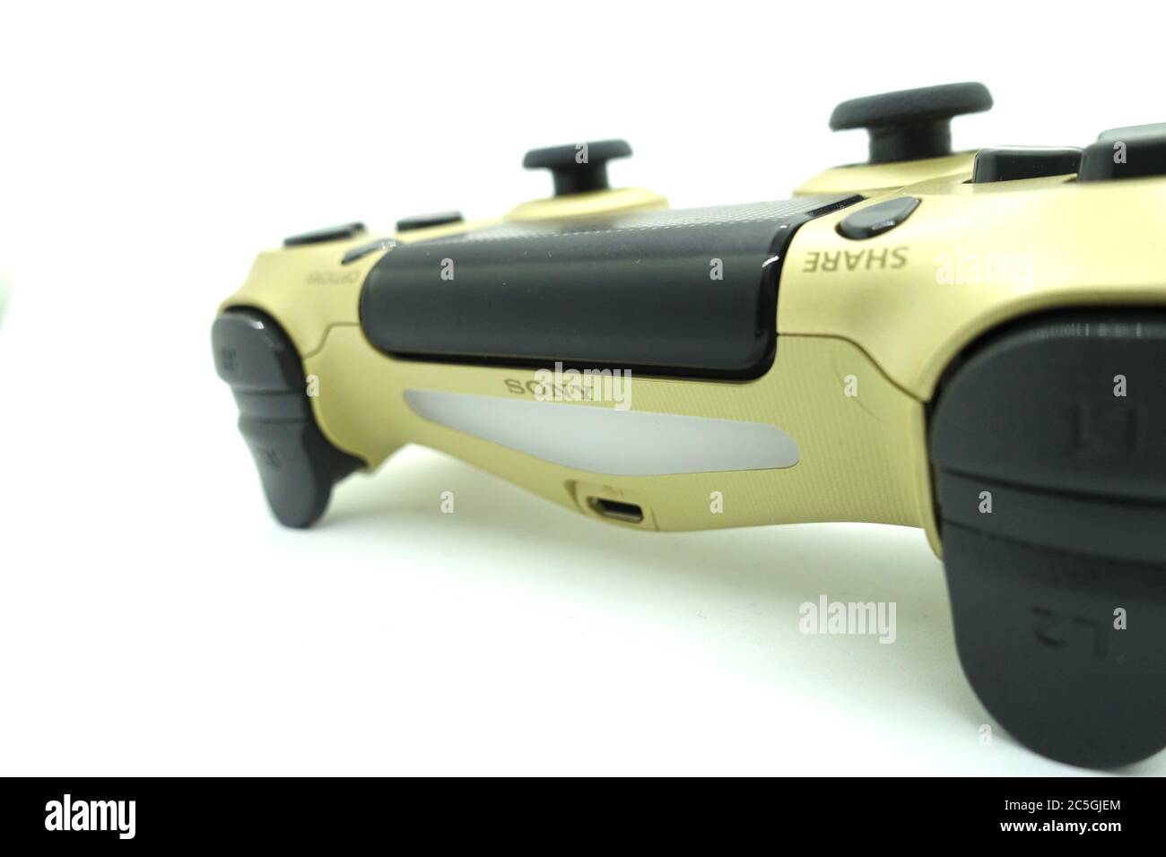 A gold colour Playstation 4 DS4 controller against isolated white ...