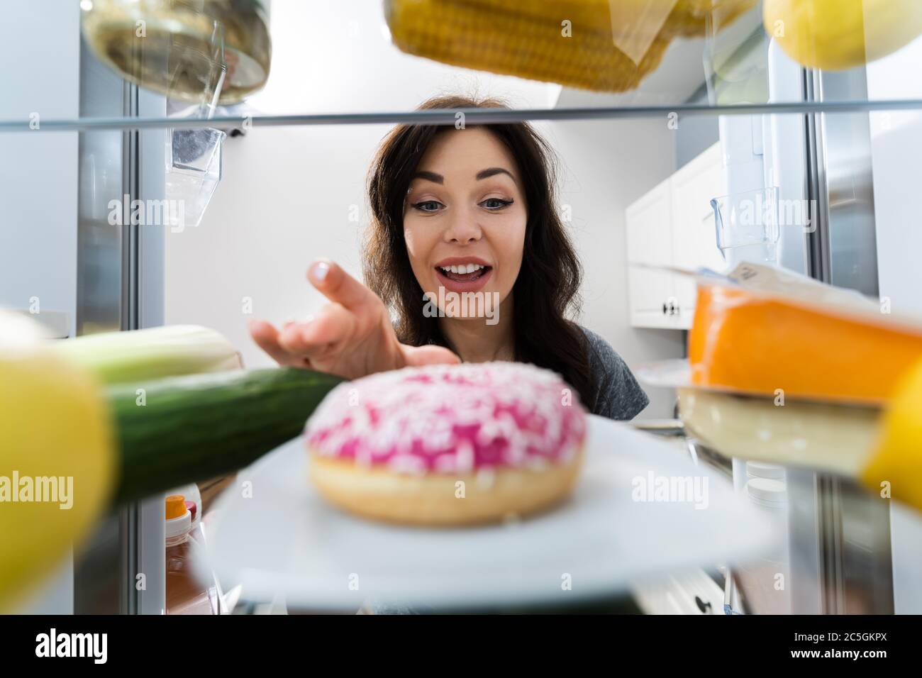 Happy Young Woman Taking Donut From Refrigerator Or Freezer Stock Photo ...