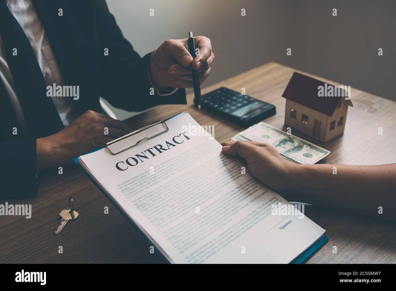 Home agents talking to home buyers who are signing contracts at the ...