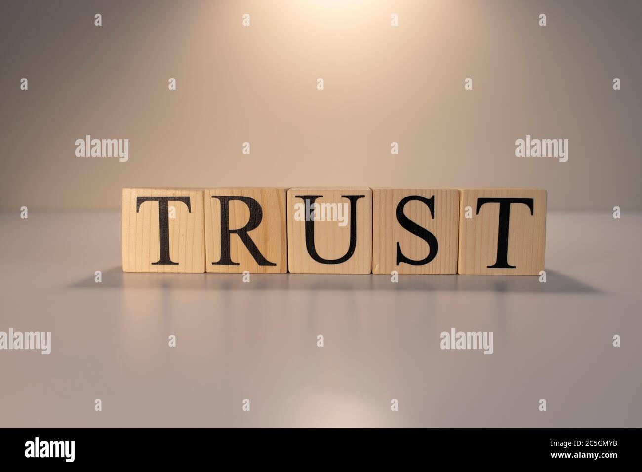 The word trust from wooden cubes. Spot light and white background ...