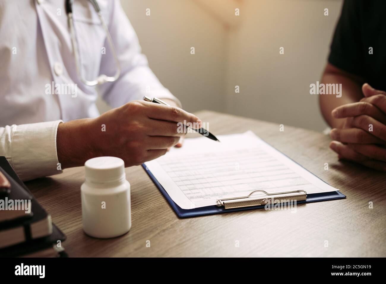 Doctor hand holding pen and talking to the patient about medication and ...