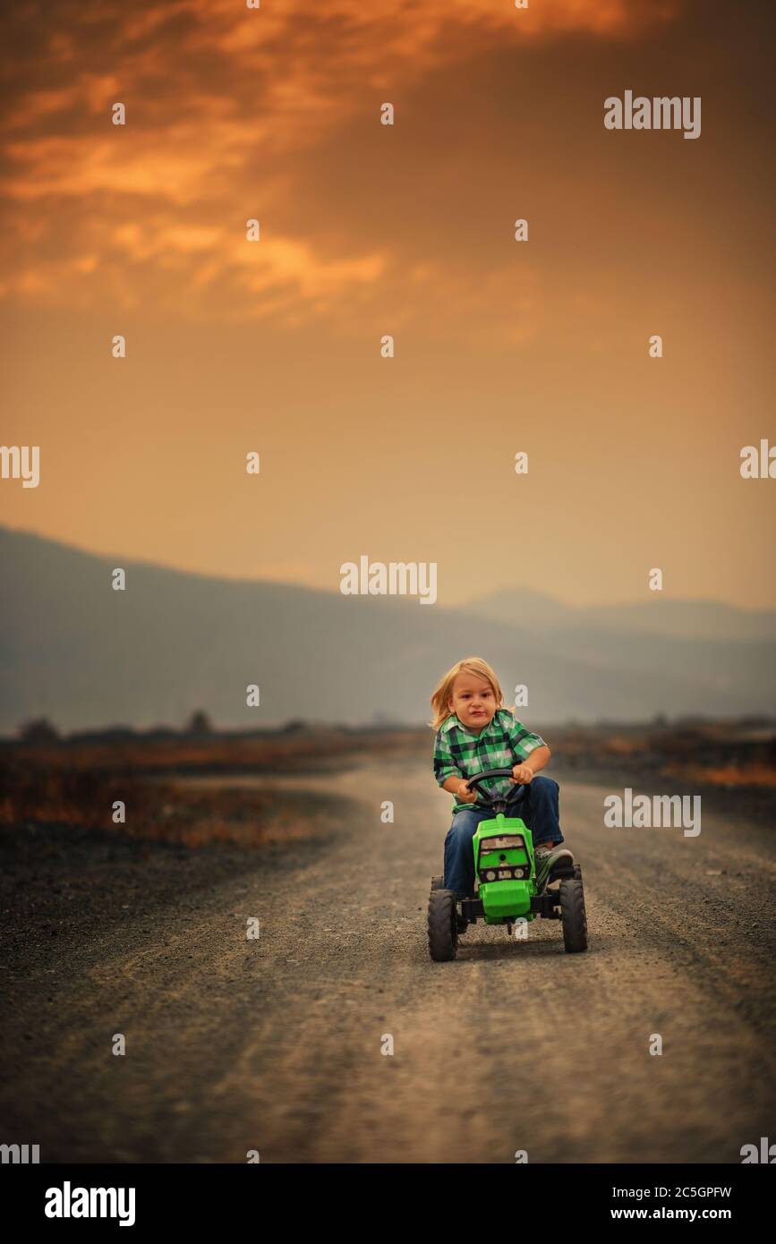boy driving toy tractor concept of a happy childhood Stock Photo - Alamy