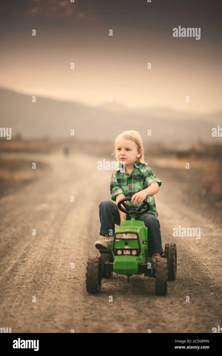 boy driving toy tractor concept of a happy childhood Stock Photo - Alamy