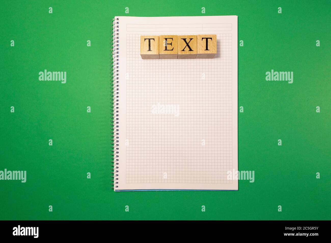 Text writing from wooden cubes. Under notepad and green background ...